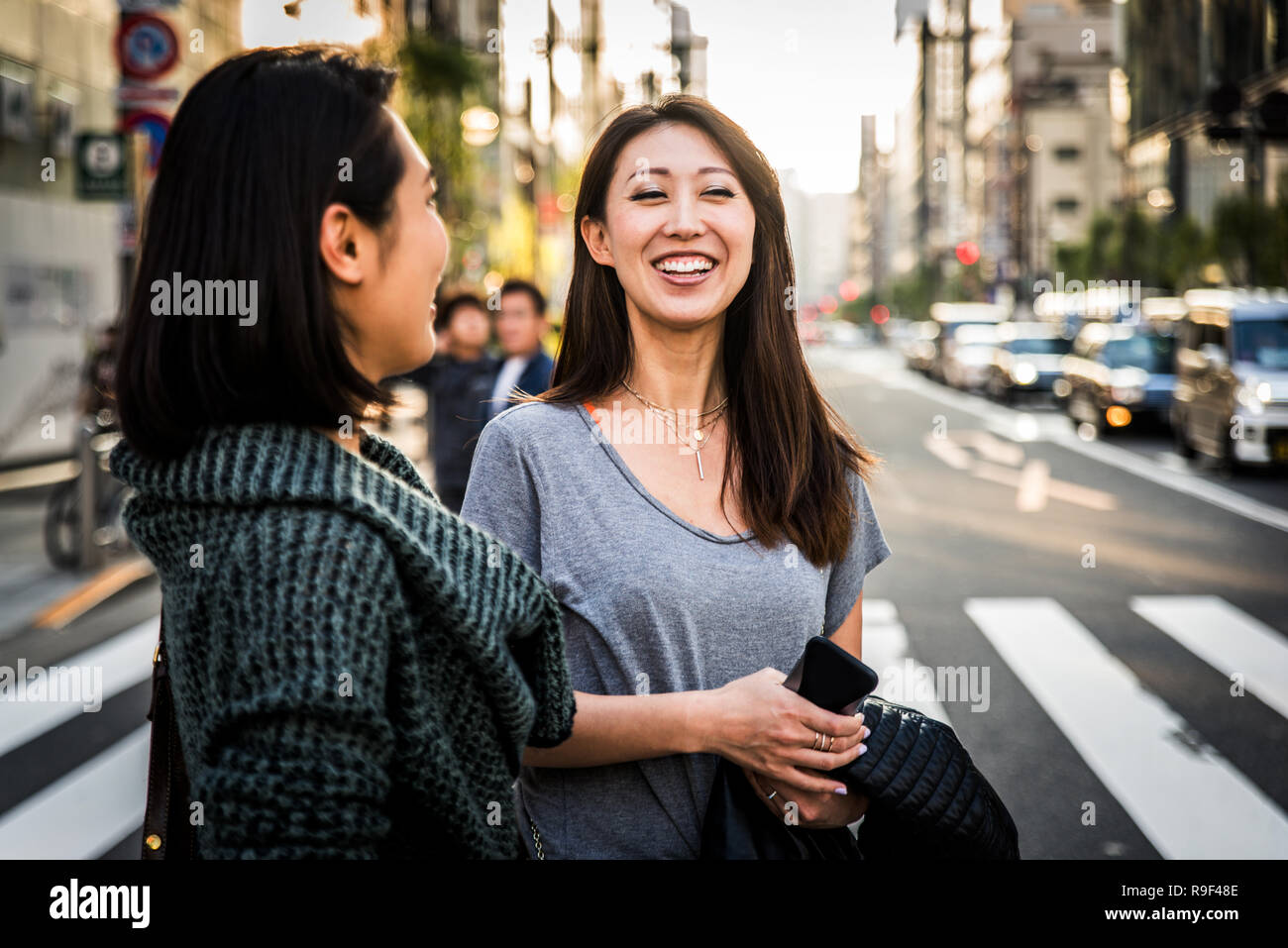 Two girlfriends meeting outdoors and having fun - Japanese people ...