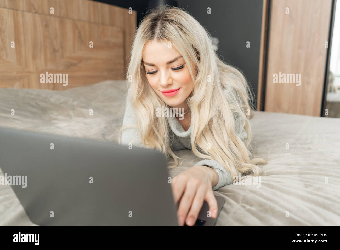 portrait of a girl behind a laptop screen. Beautiful blonde woman lying ...