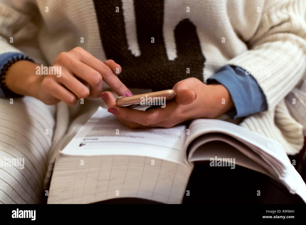 Student reading a book and using her phone at the same time. Technology ...