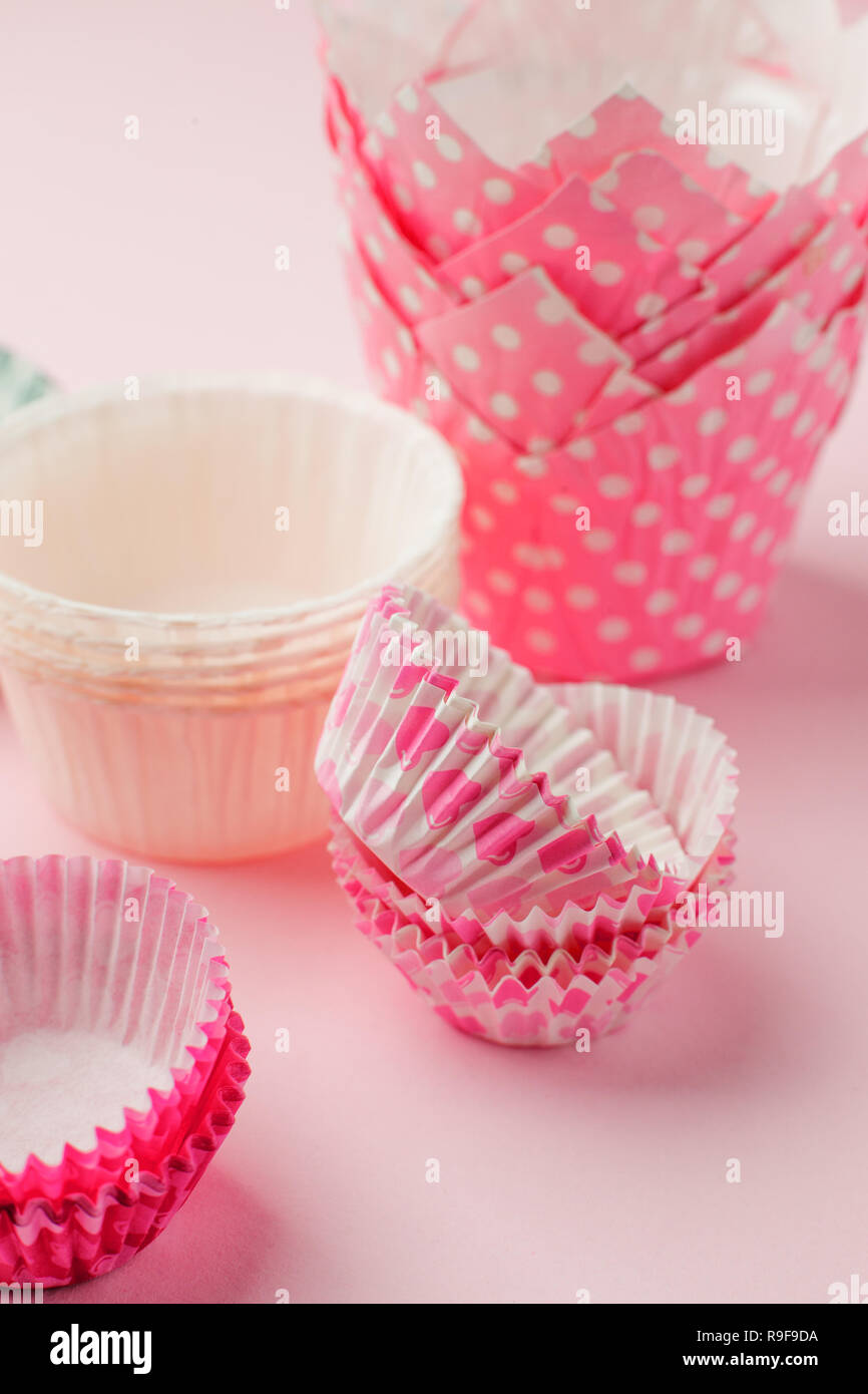 Cupcake cases tower in variety of color and size on pink table ready ...