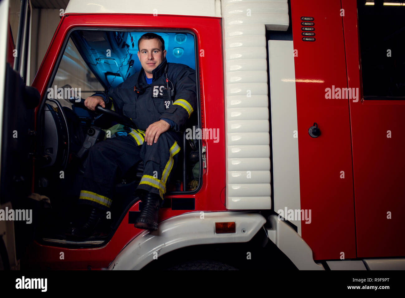Photo of young fireman man sitting in fire truck at station Stock Photo ...