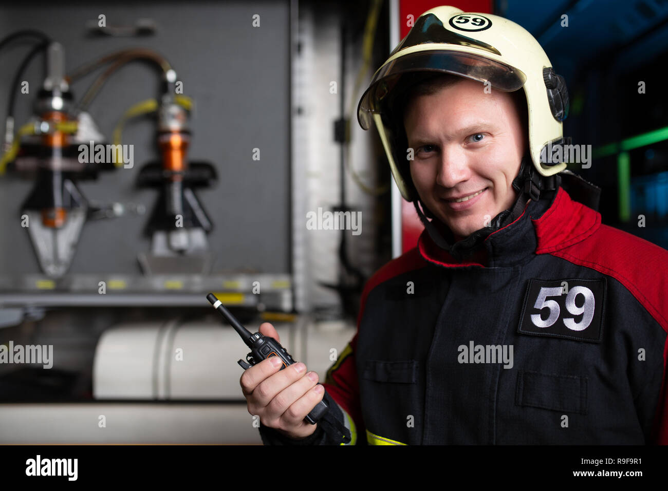 Photo of man fireman with walkie-talkie in hands on background of fire ...