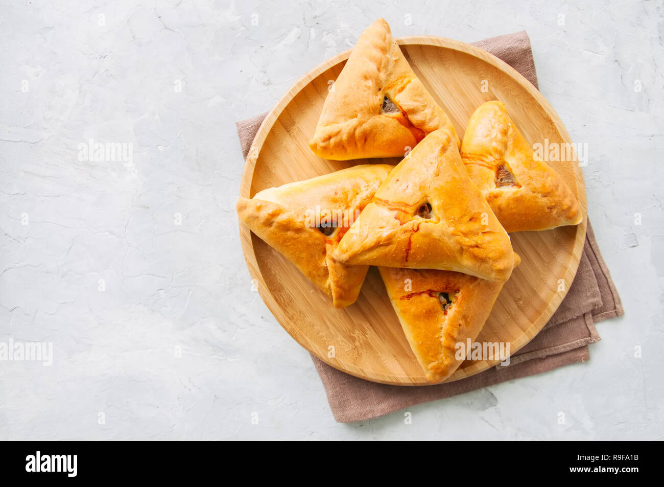 Homemade baked uchpuchmak (samsa) with meat and potato on a wooden ...