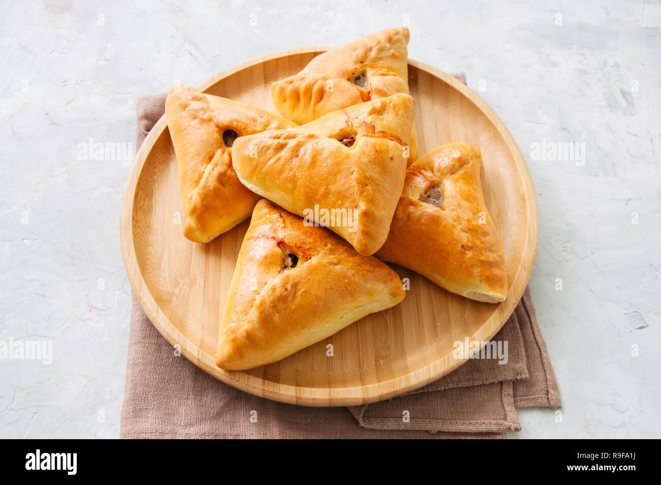 Homemade baked uchpuchmak (samsa) with meat and potato on a wooden ...