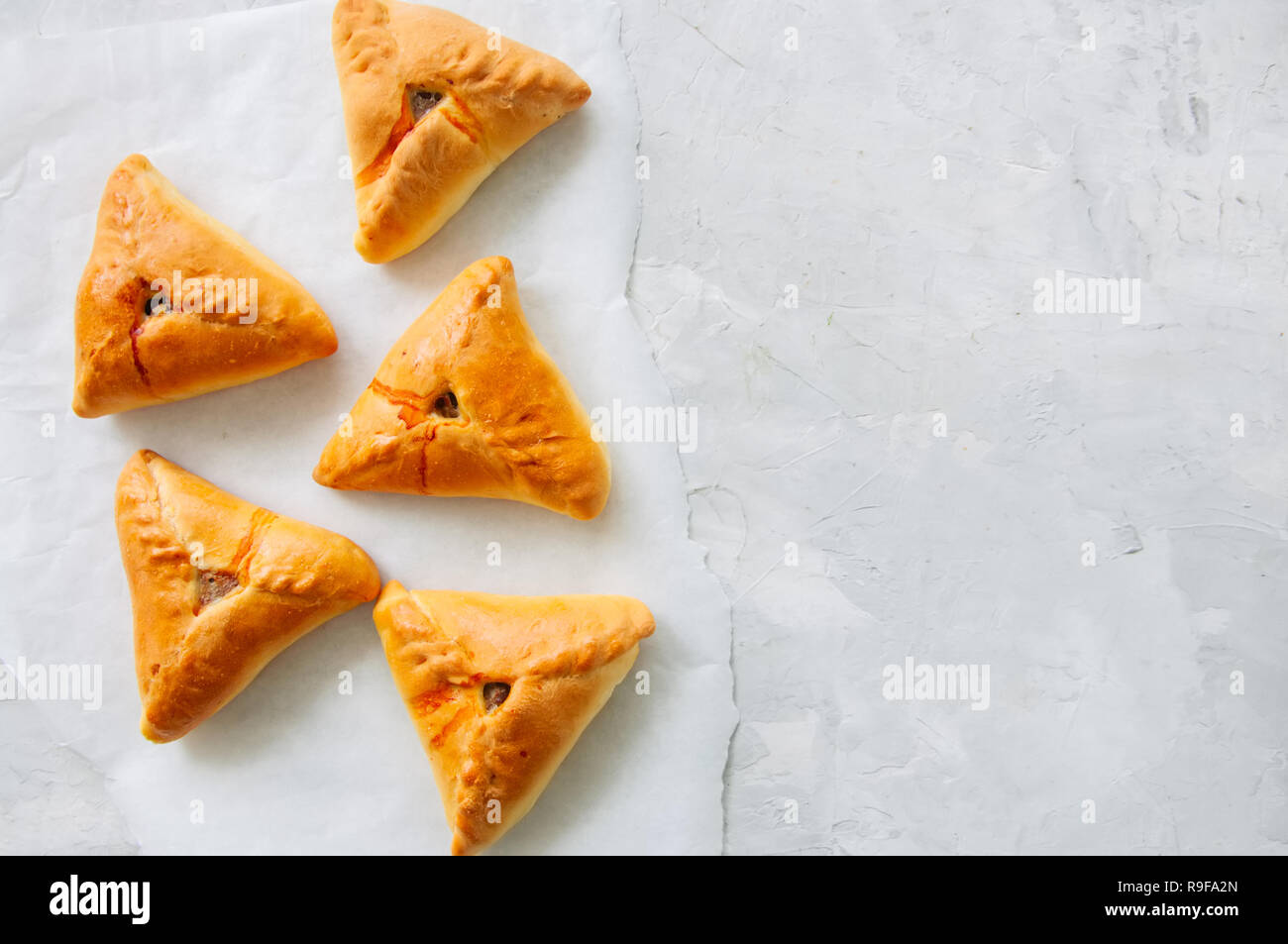 Homemade baked uchpuchmak (samsa) with meat and potato on a white stone ...