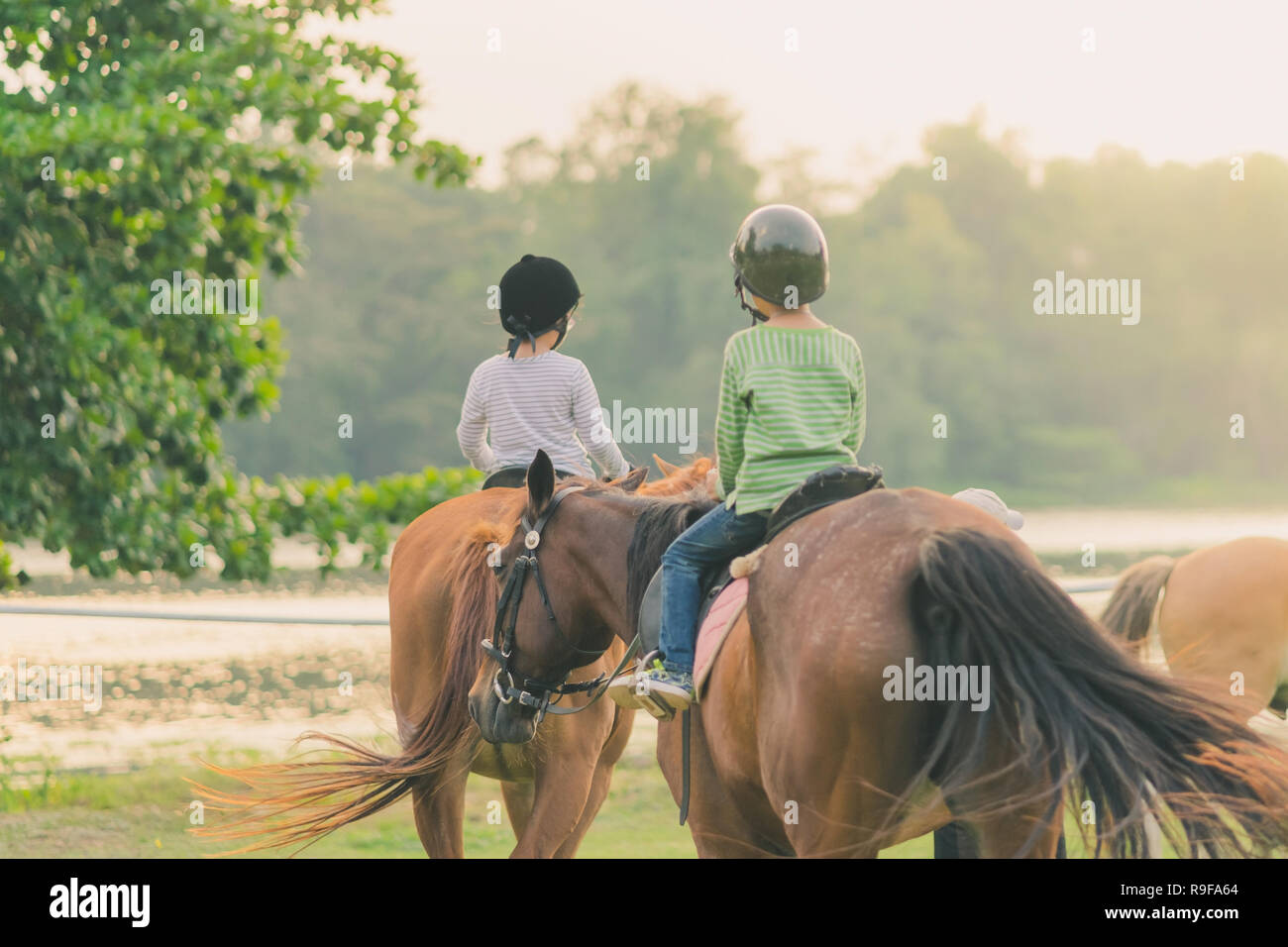 Kids learn to ride a horse near the river before sunset Stock Photo - Alamy