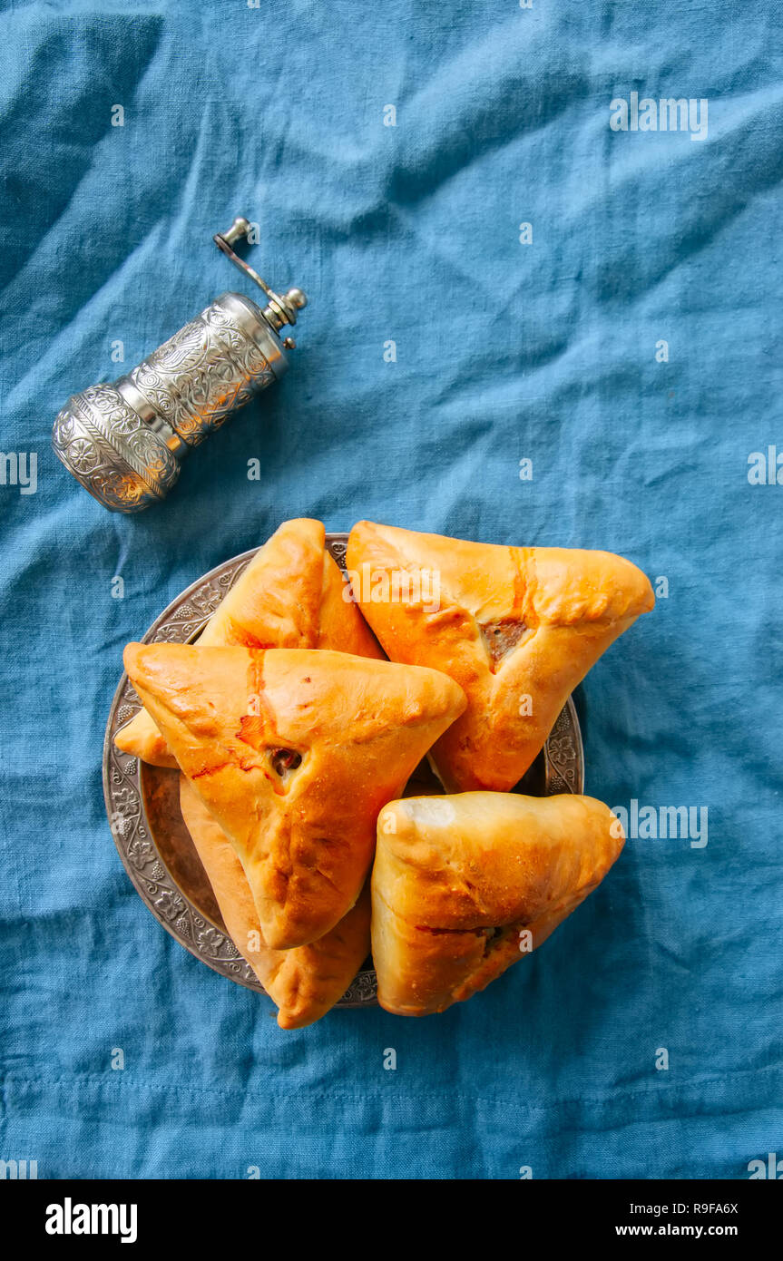 Homemade baked uchpuchmak (samsa) with meat and potato served on a ...