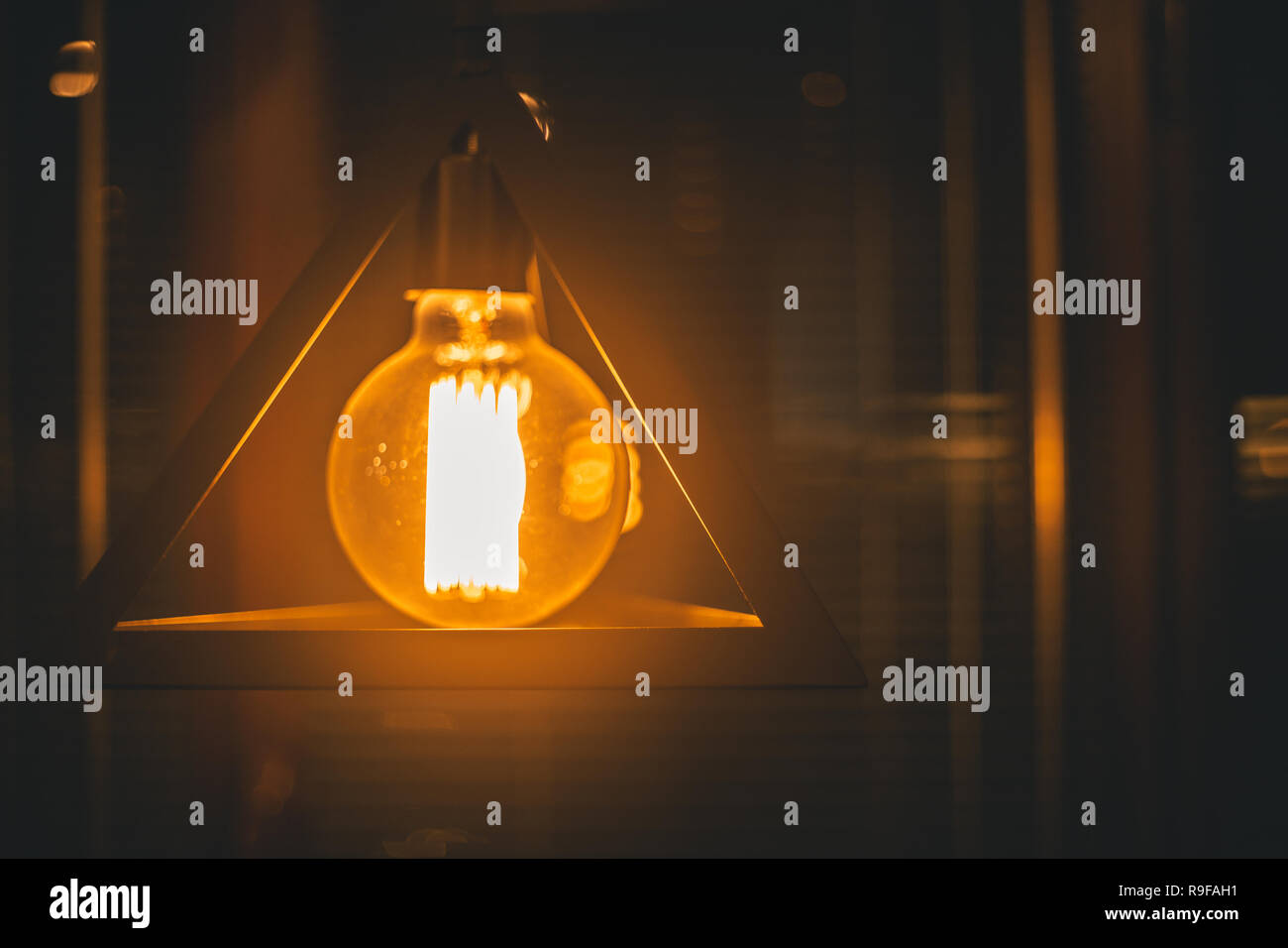Ceiling light. Light bulb in triangular metal structure Stock Photo - Alamy