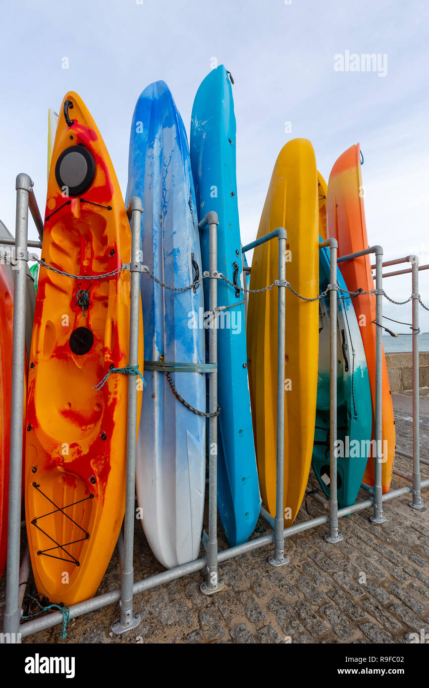 Multi-coloured sea canoes in storage rack at St Ives harbour, on the ...