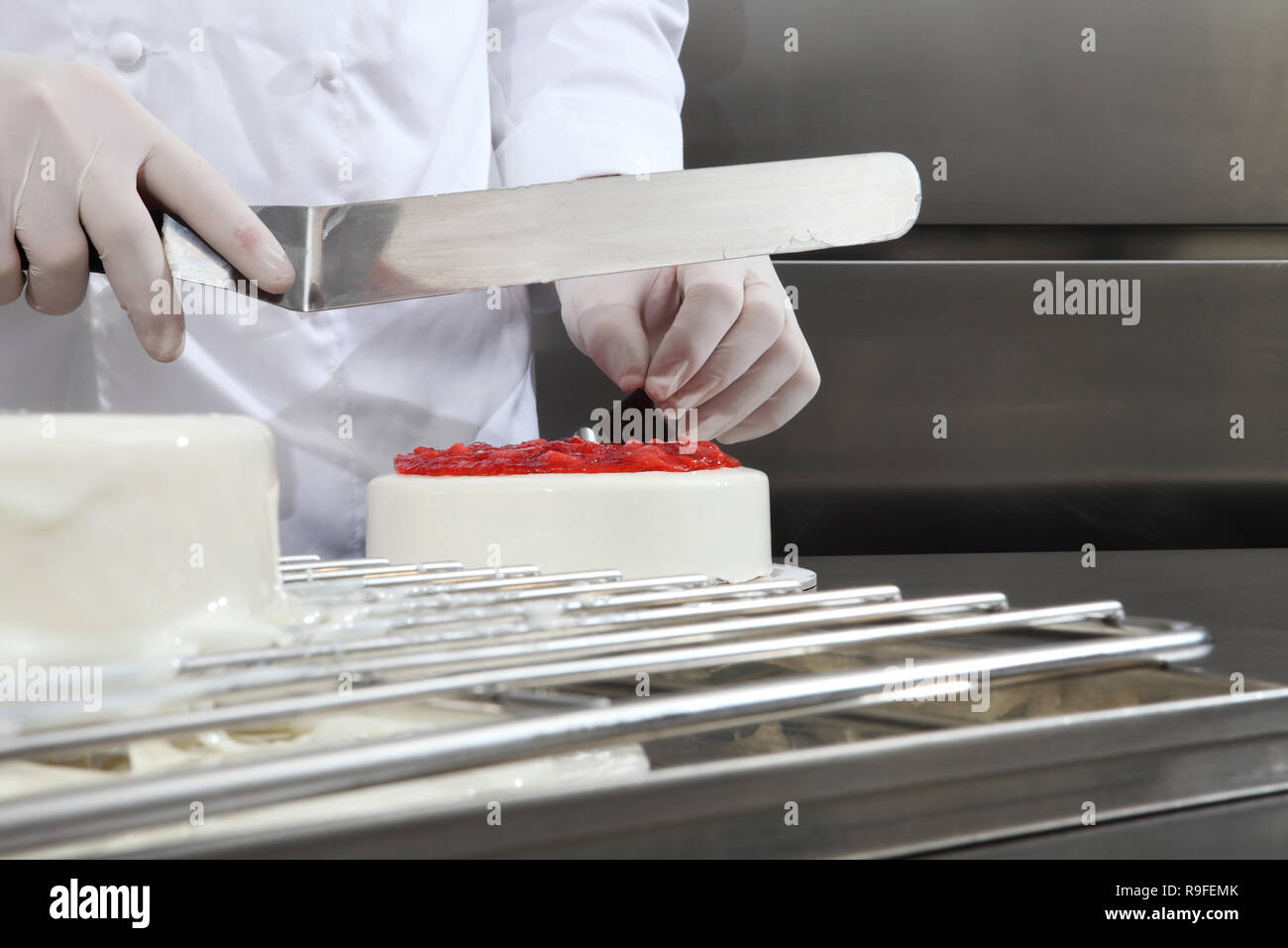 hands pastry chef prepares a cake, cover with icing and decorate with ...