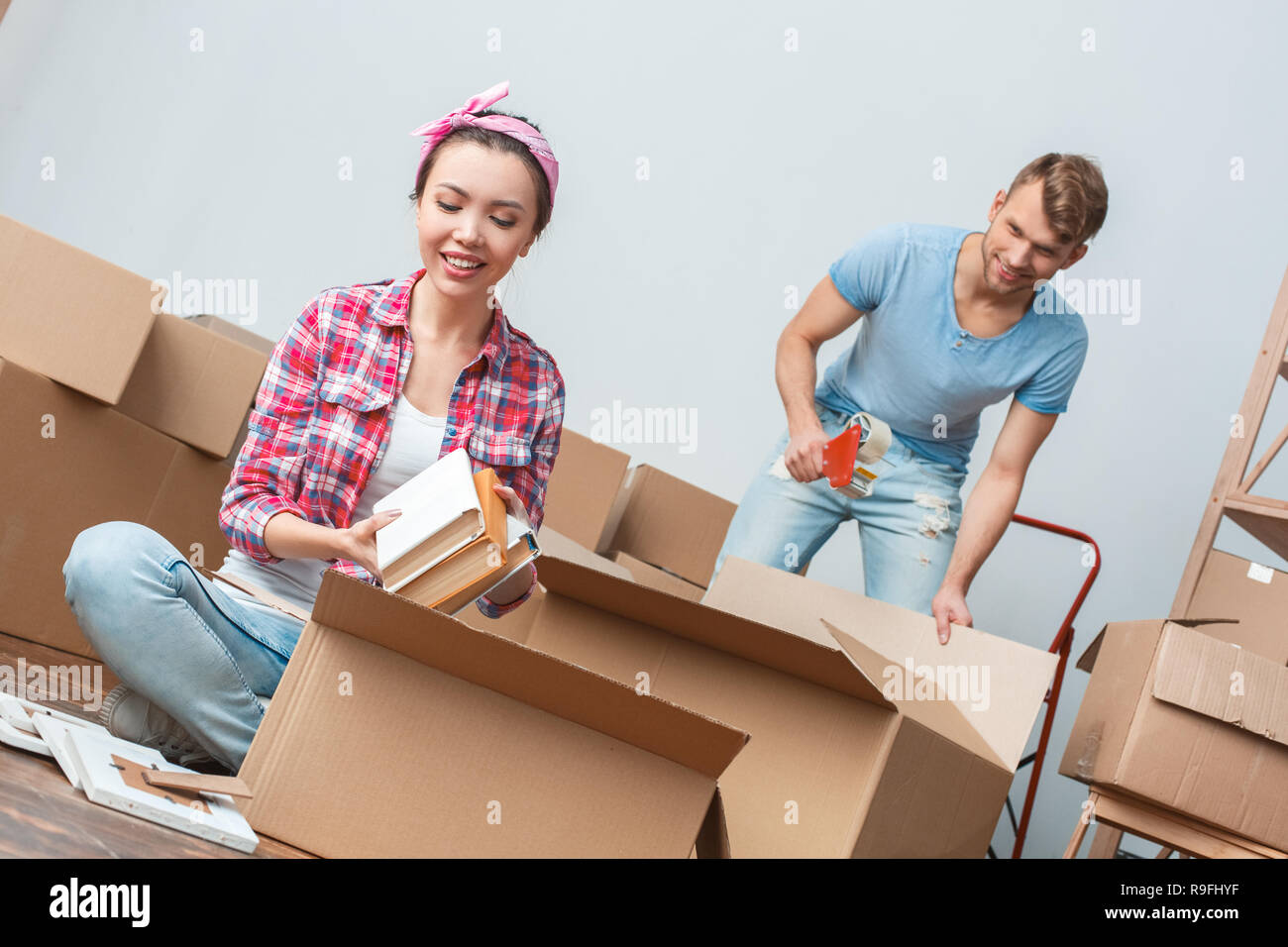 Young husband and wife moving to new place packing things woman putting ...