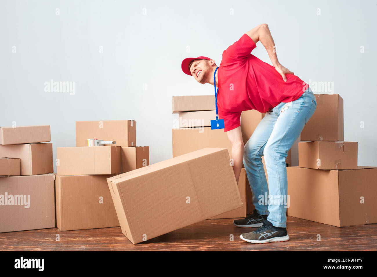 Young delivery man isolated on white wall standing bending down ...