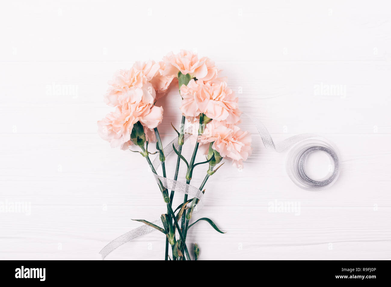 Pale pink ink flowers with silver ribbon on white background, top view ...