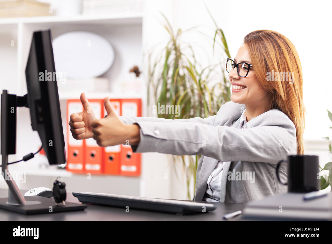 businesswoman thumbs up infront of a computer in an office Stock Photo ...