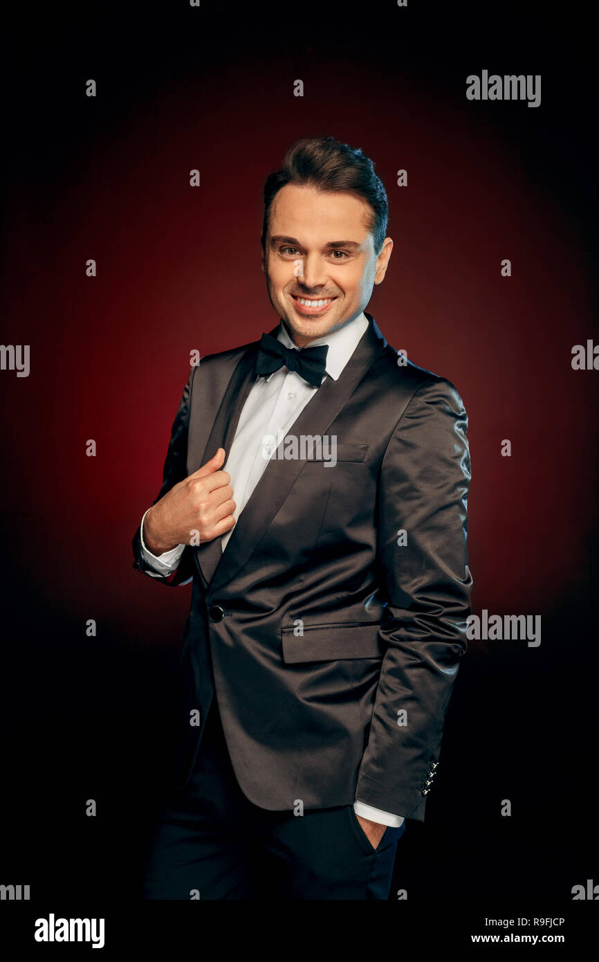 Professional showman wearing suit standing isolated on black and red ...