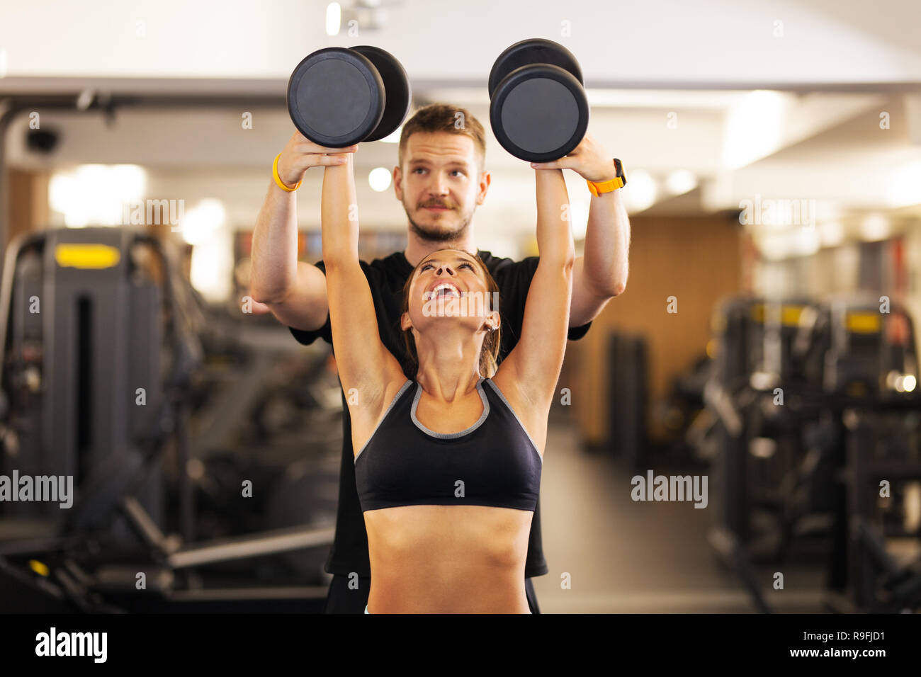 happy girl with fitness coach lifting weights Stock Photo - Alamy