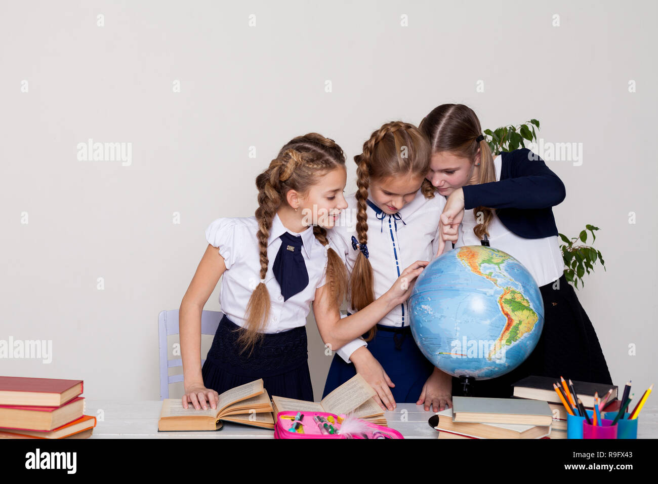 three girls in the classroom studying geography globe of planet Earth ...