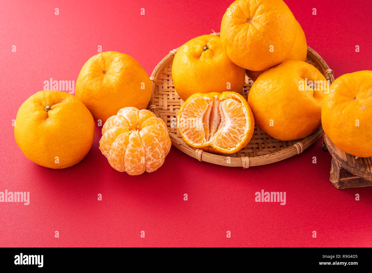 Beautiful and delicous tangerine isolated on red background with bamboo ...