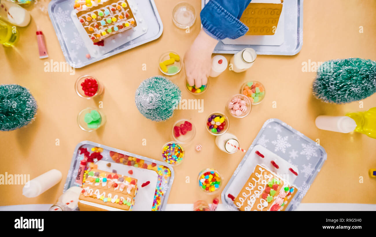 Flat lay. Kids decorating small gingerbread houses at the Christmas ...