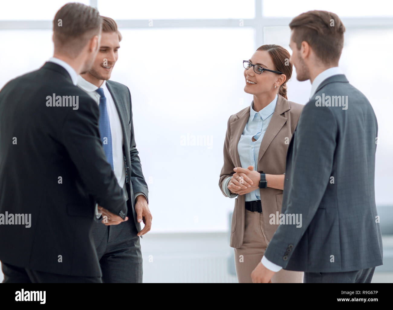 group of employees talking while standing in the office Stock Photo - Alamy
