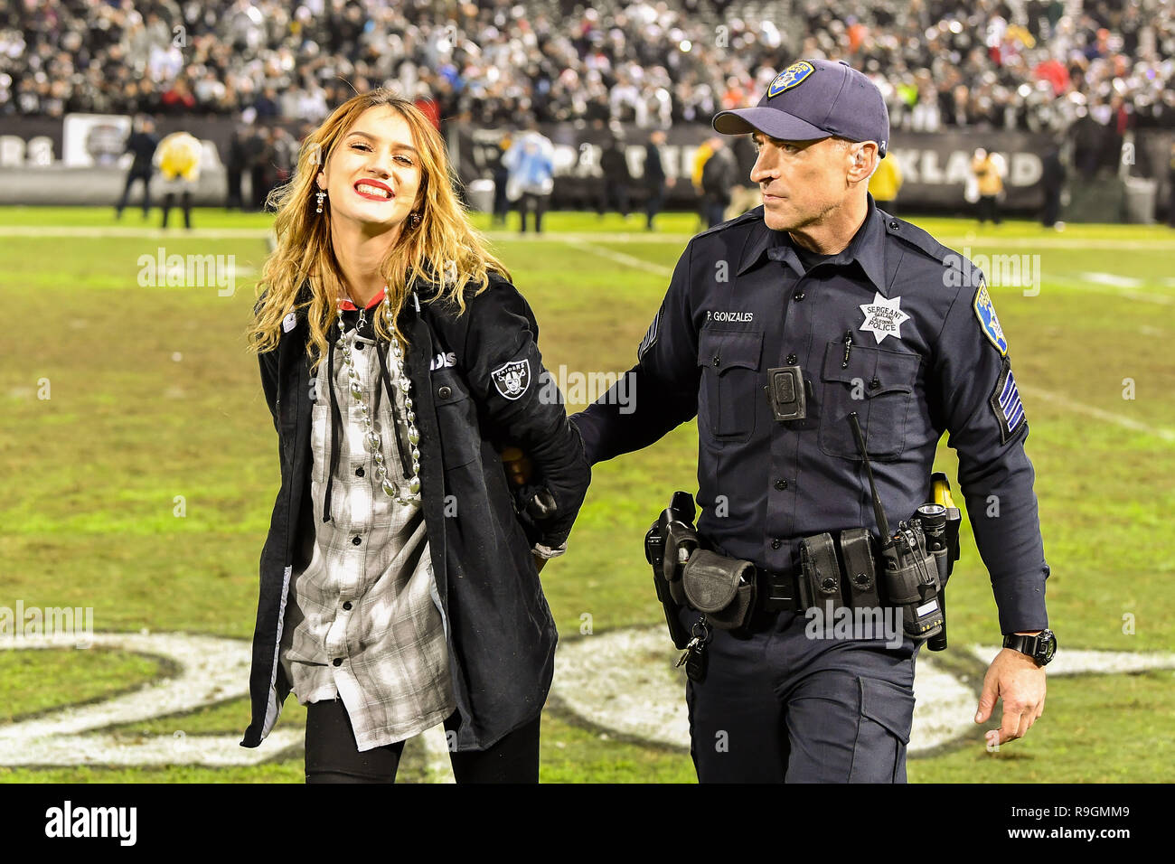 Oakland, CA. 24th Dec, 2018. A female fan is escorted off the the field ...