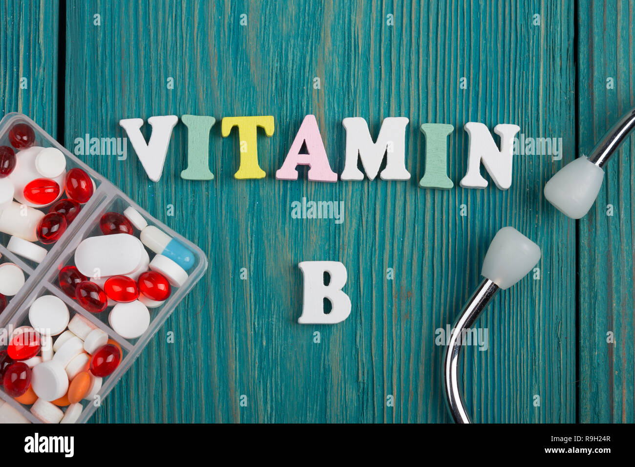 Text "Vitamin B" of colored wooden letters, stethoscope and pills on a ...
