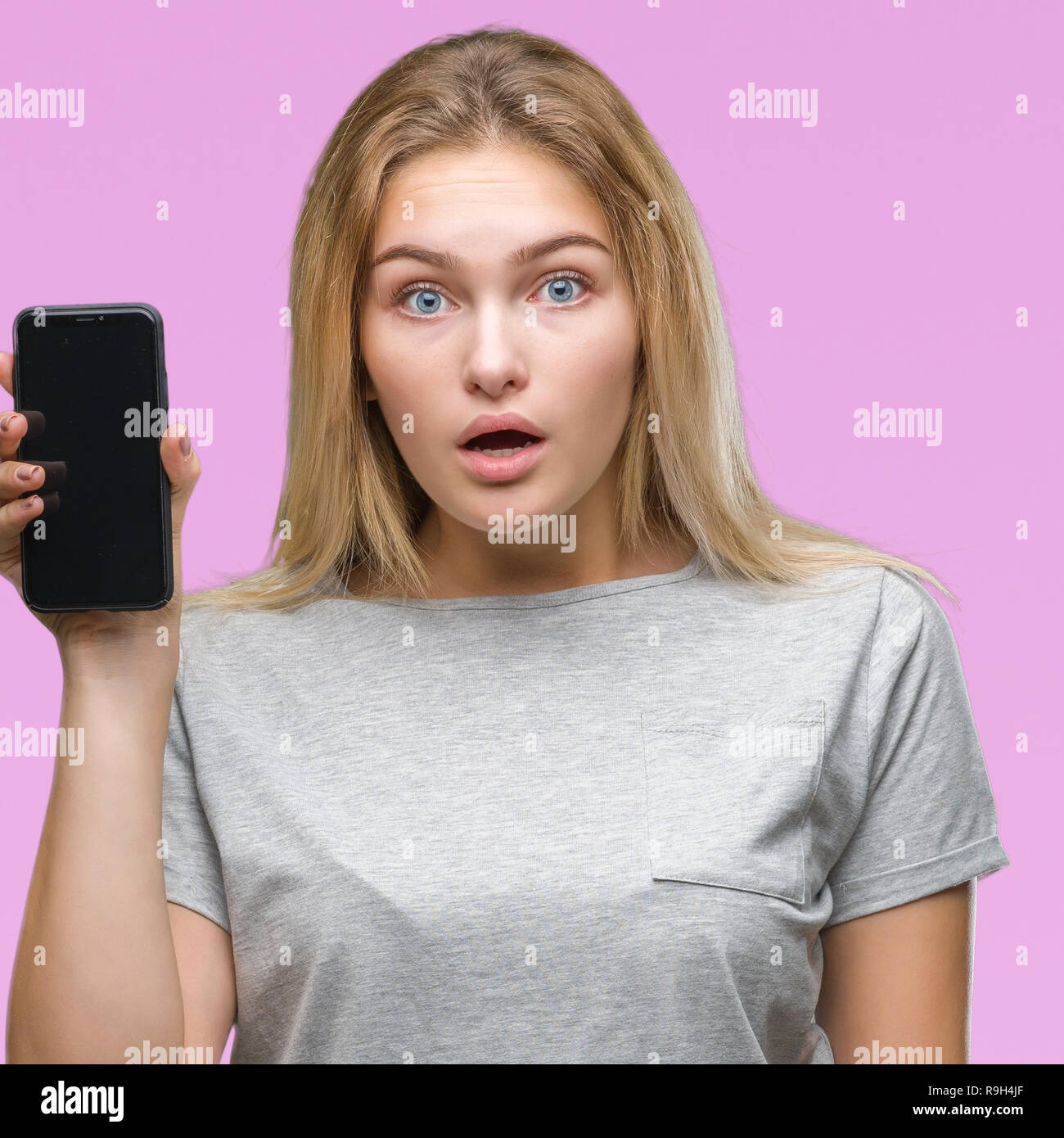 Young caucasian woman showing screen of smartphone over isolated ...