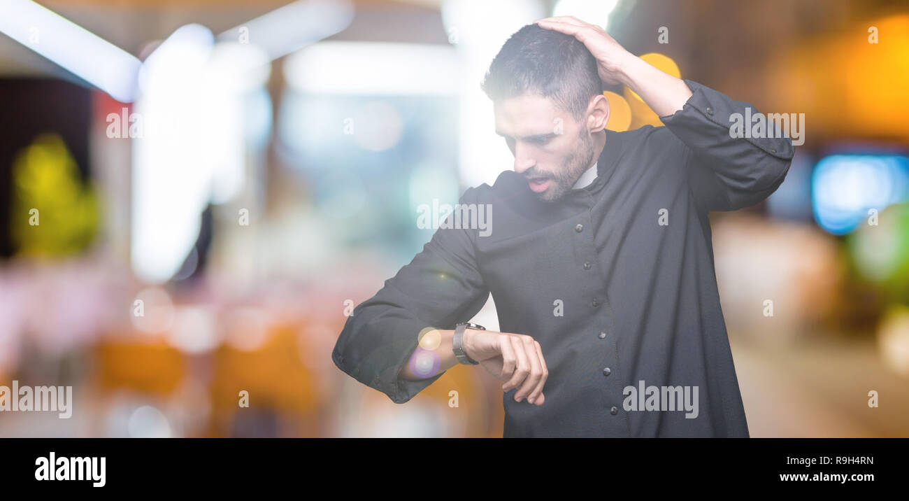 Young Christian priest over isolated background Looking at the watch ...