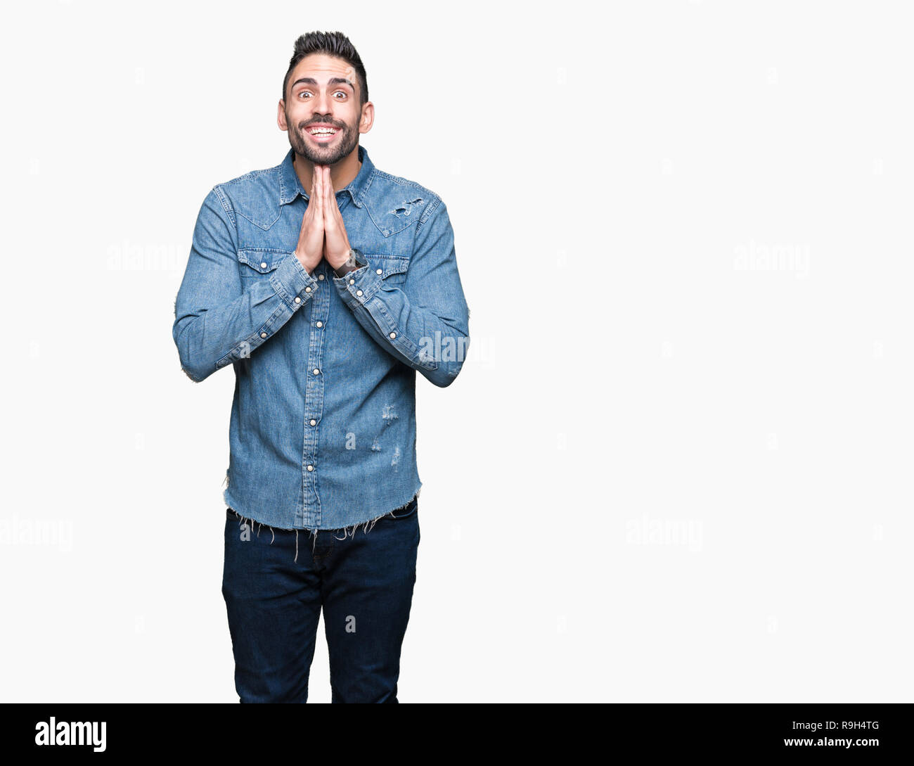Young handsome man over isolated background praying with hands together ...