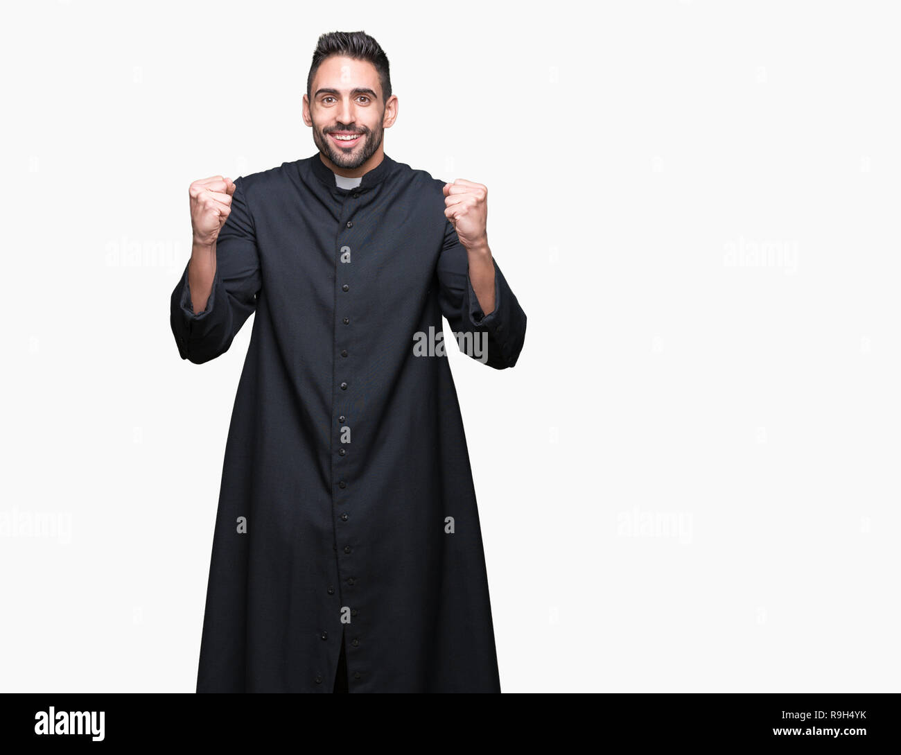 Young Christian priest over isolated background celebrating surprised ...