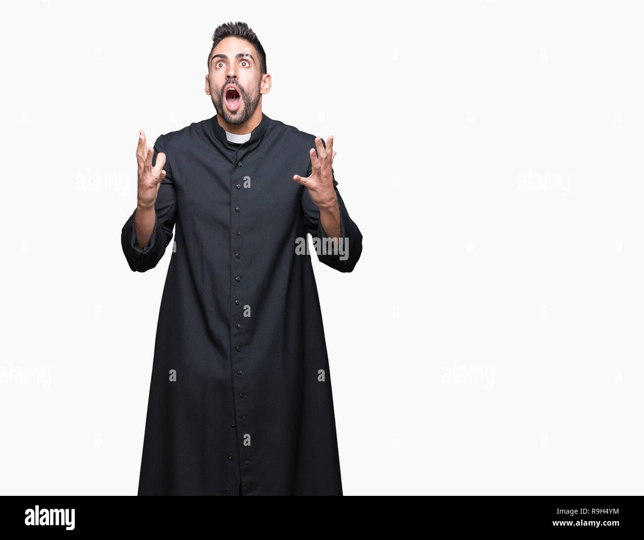 Young Christian priest over isolated background crazy and mad shouting ...