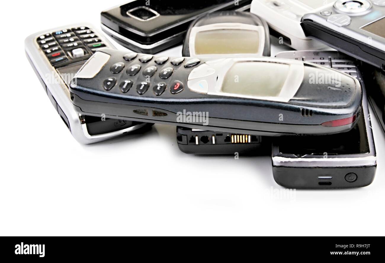 old mobile phones piled up on a table with white background no people ...