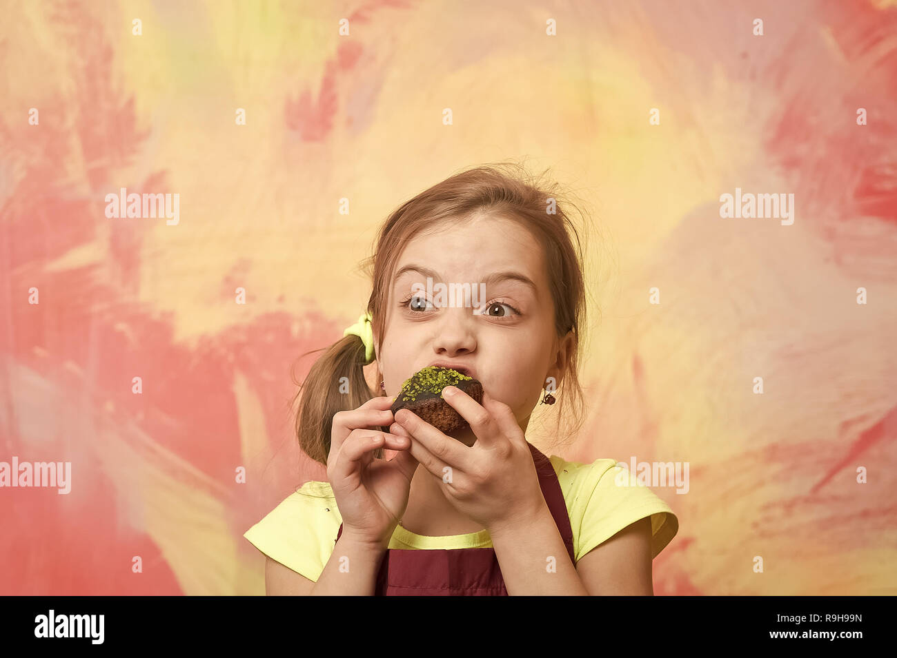 Baking and delicious bakery. Girl eating cupcake. Baby cook in red chef ...