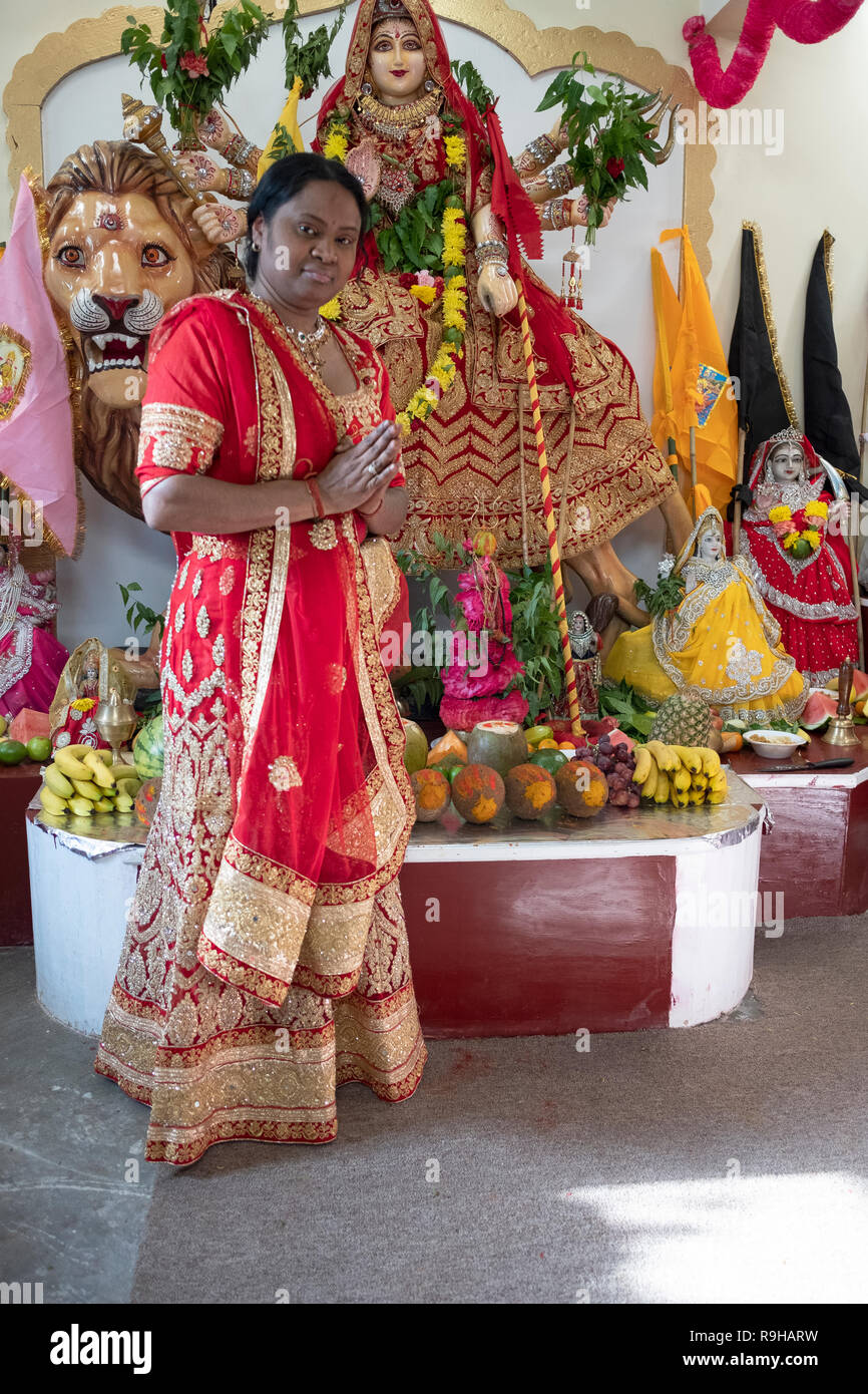 Portrait of a female Hindu Priest in front of a statue of the goddess ...