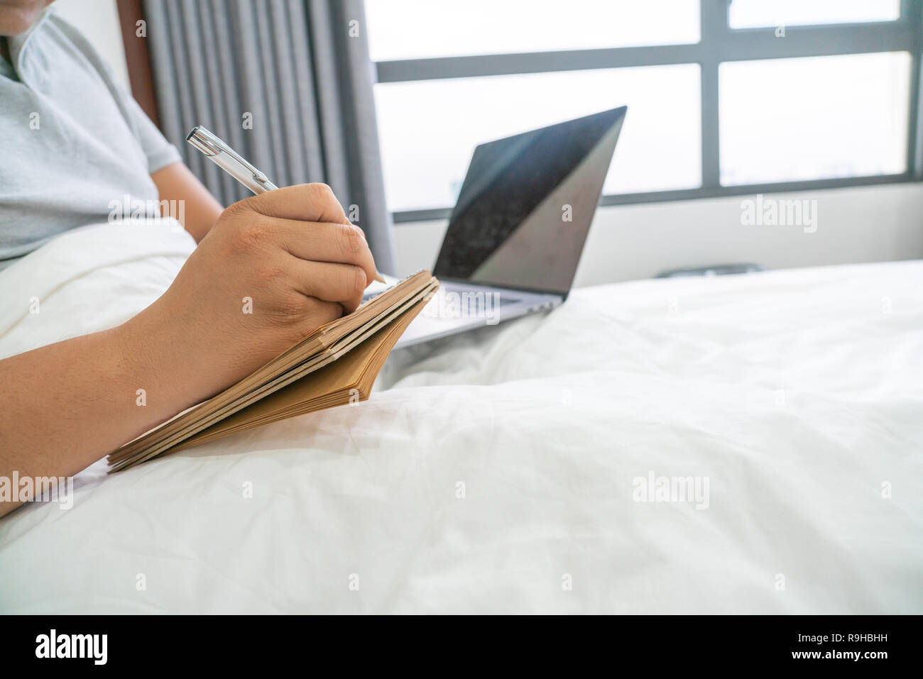 Side view of young businessman writing notes on bed Stock Photo - Alamy