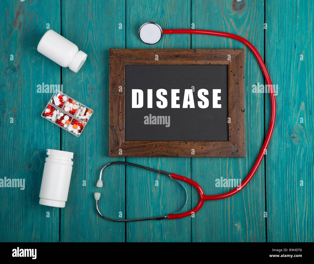 Medecine concept - Blackboard with text "Disease", book, pills and ...