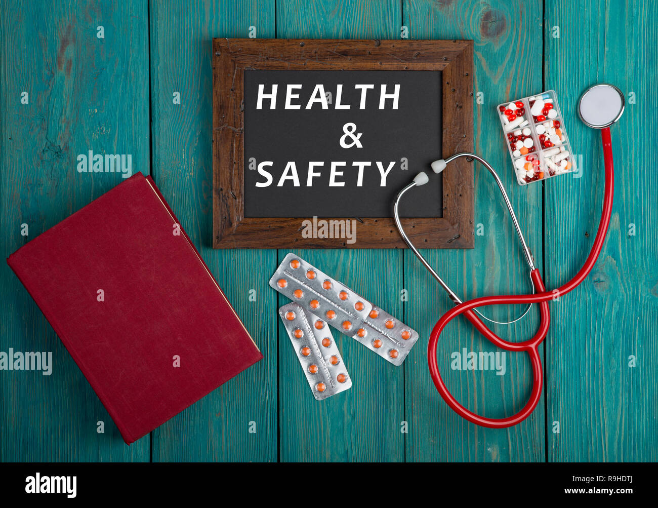 Medecine concept - Blackboard with text "Health & Safety", book, pills ...