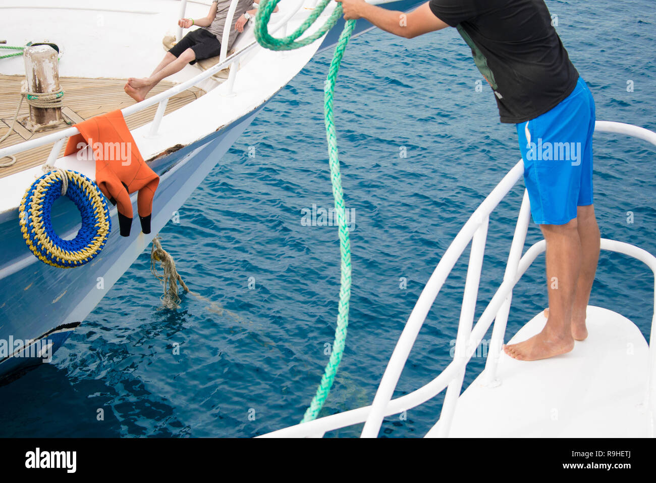 a sailor with a rope stands on the bow of the yacht and waits for ...