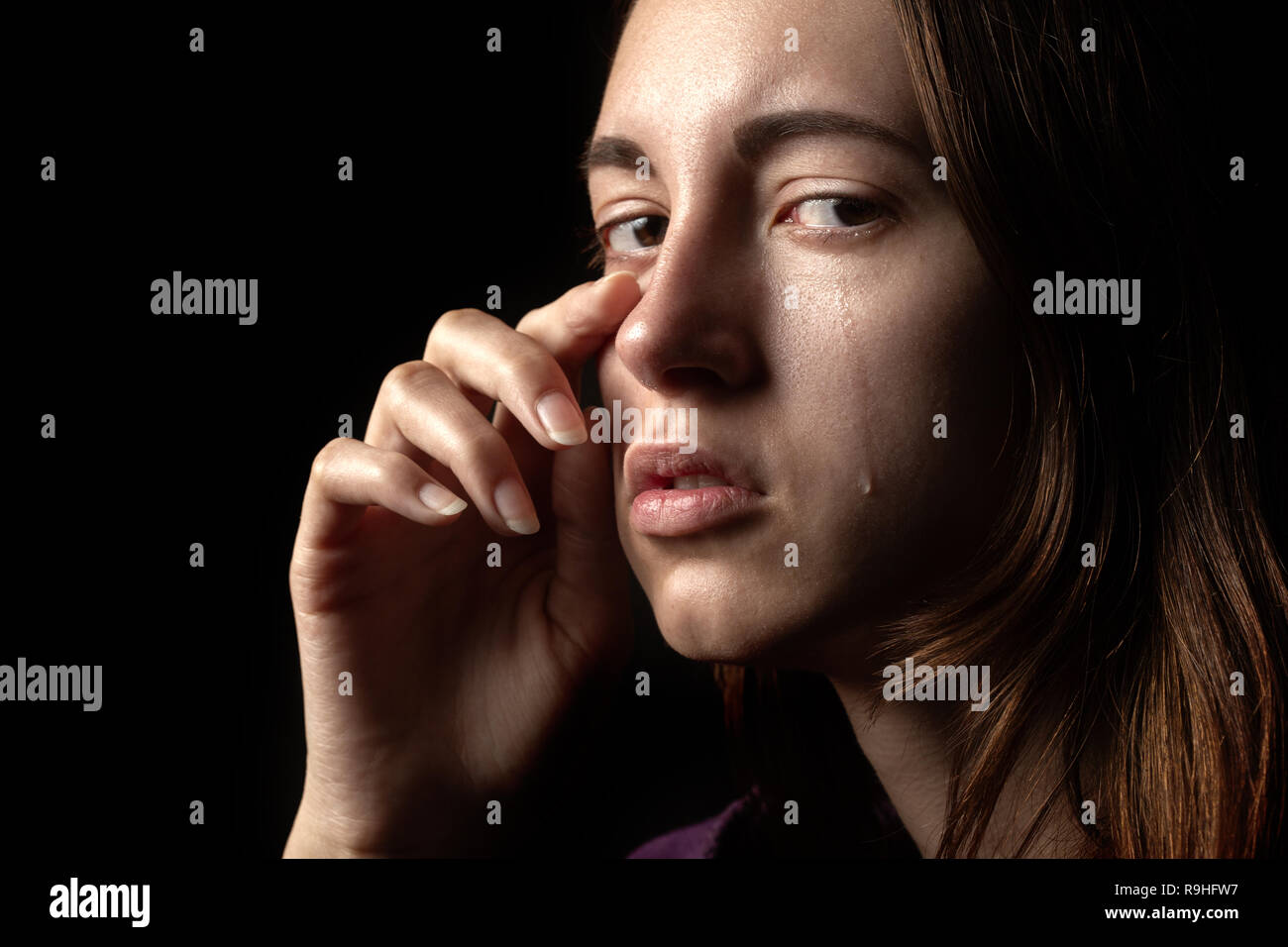 sad woman crying on black background, looking at camera, closeup ...