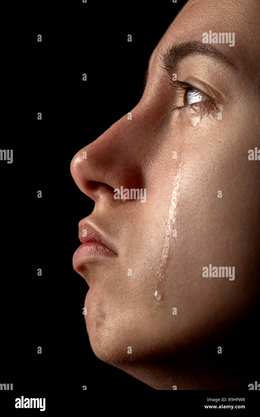 sad woman crying, looking up on black background, closeup portrait ...