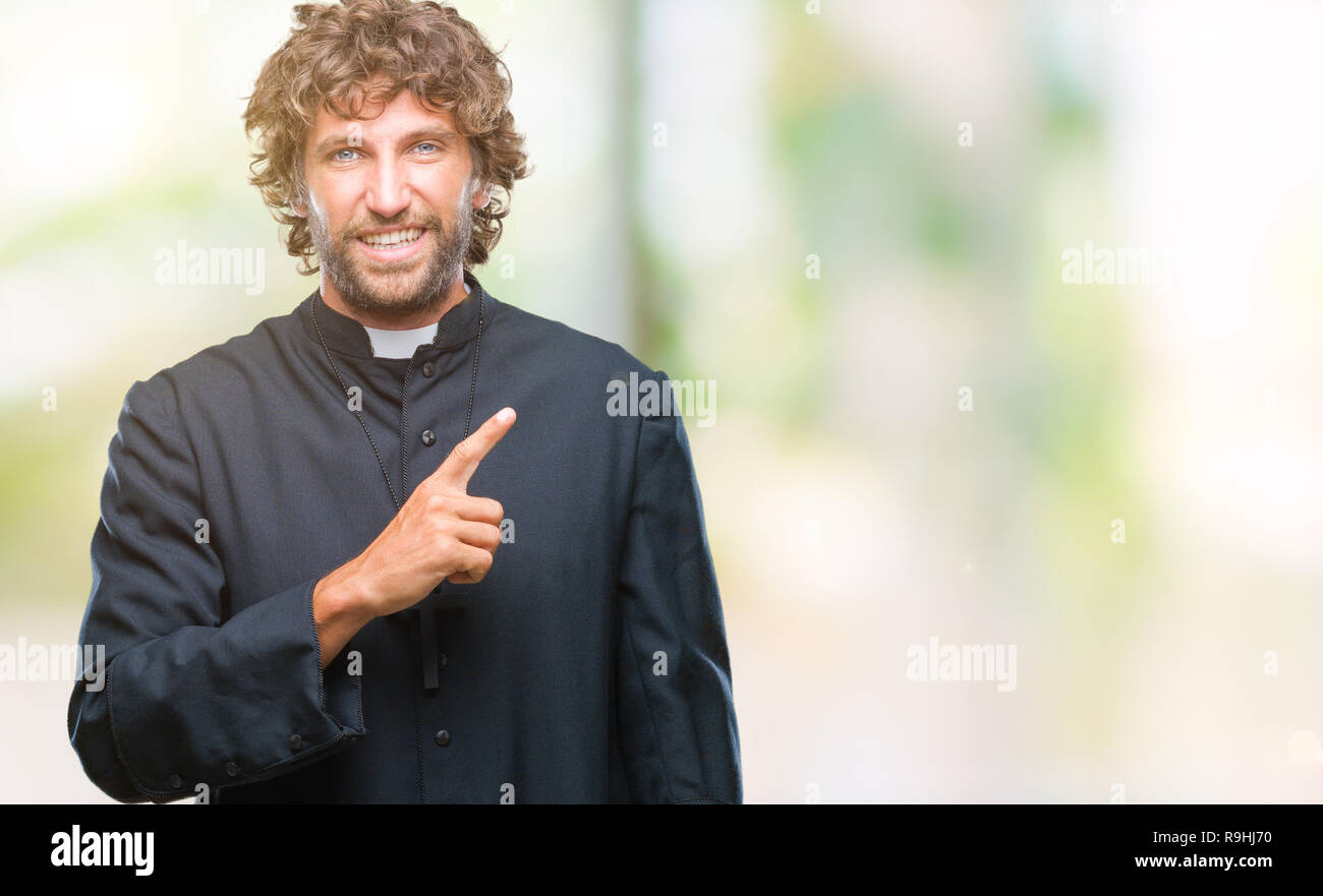 Handsome hispanic catholic priest man over isolated background cheerful ...