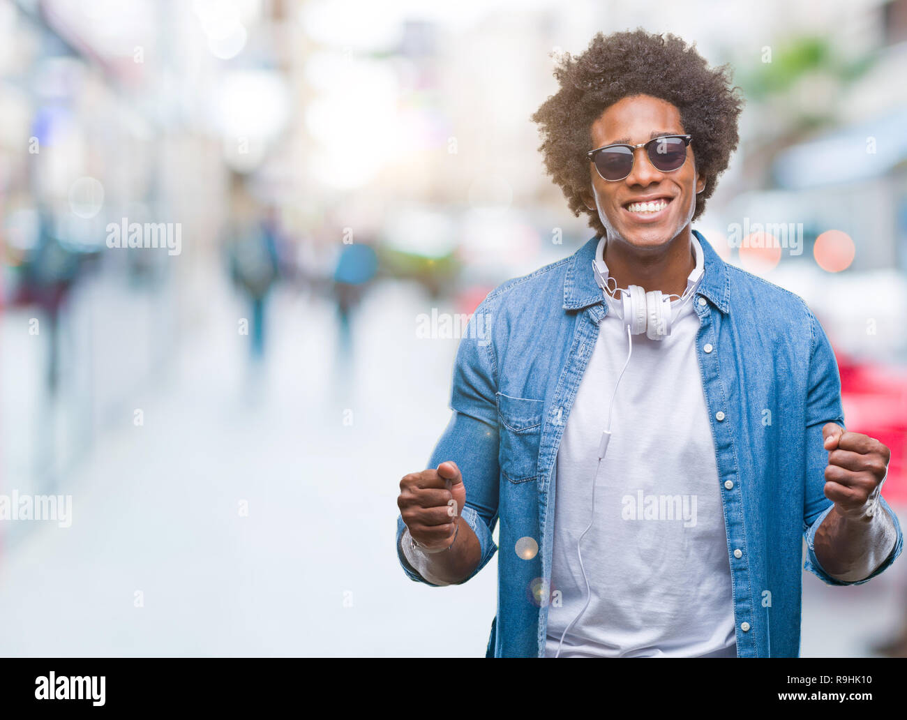 Afro american man wearing headphones listening to music over isolated background very happy and ...