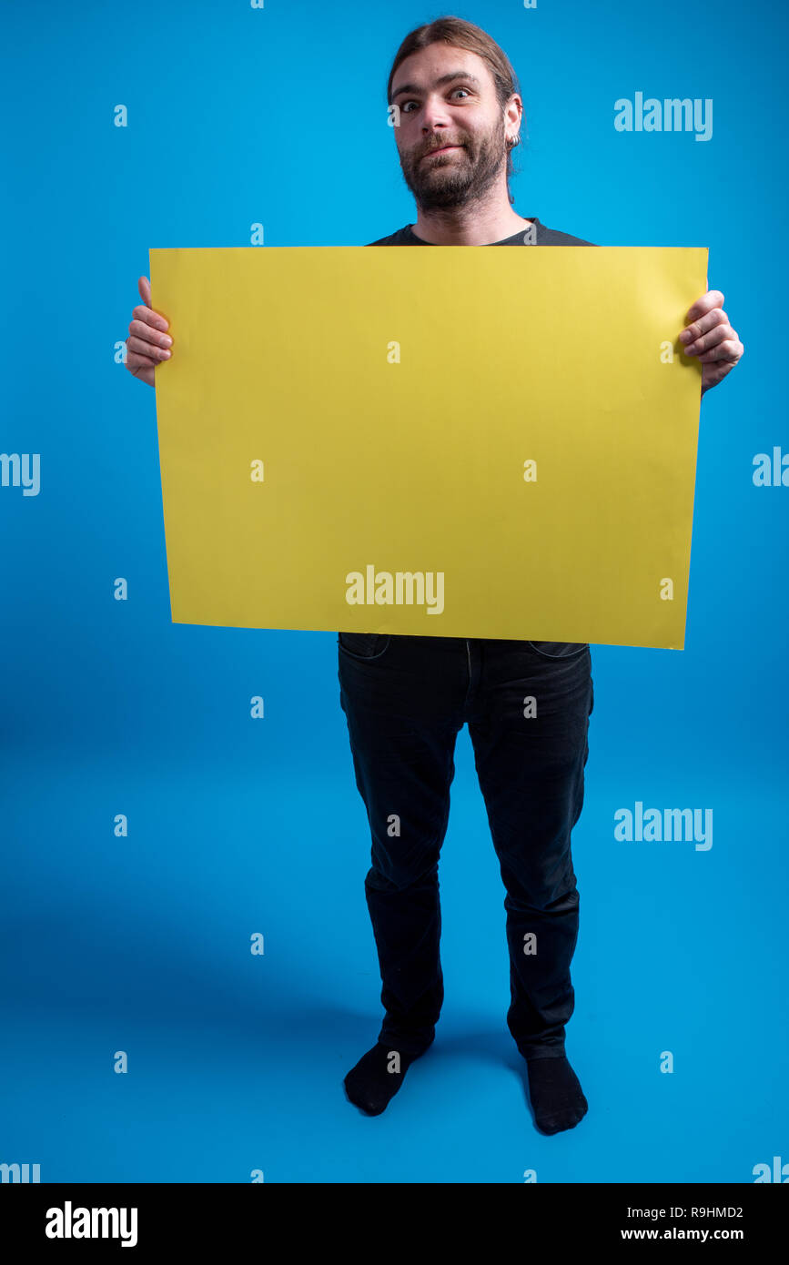 Full portrait of funny man holding a cardboard billboard. Advertisement ...
