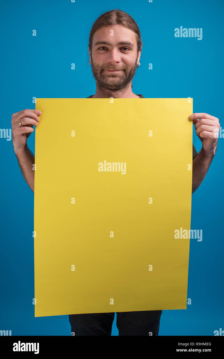 Male holding a yellow cardboard vertically. Looking satisfied while ...
