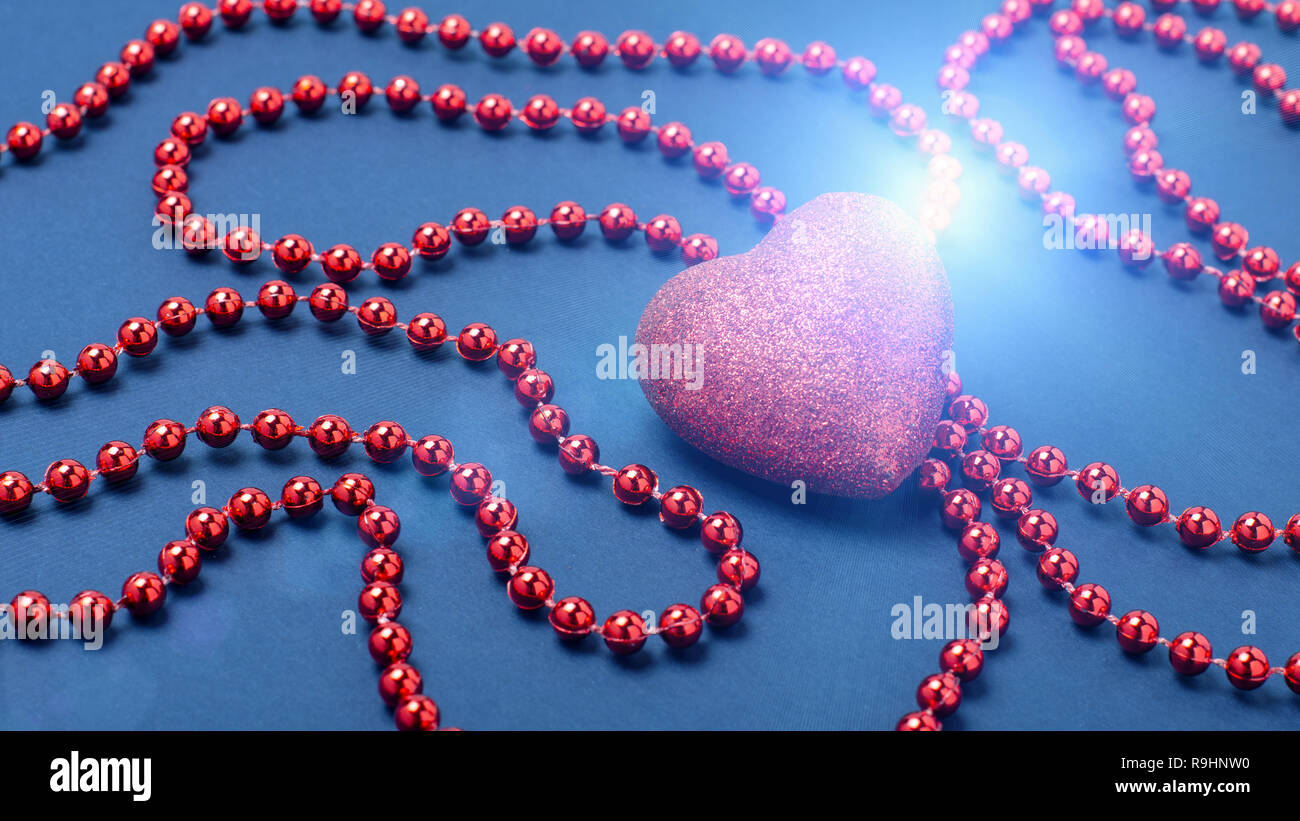 red heart on a blue paper background with red beads and flare flare ...
