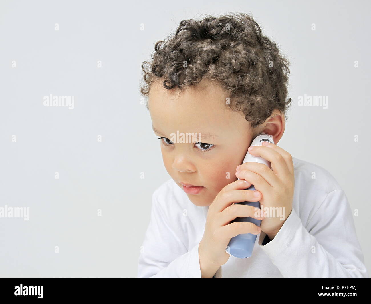child takes temperature with ear thermometer at home on white ...
