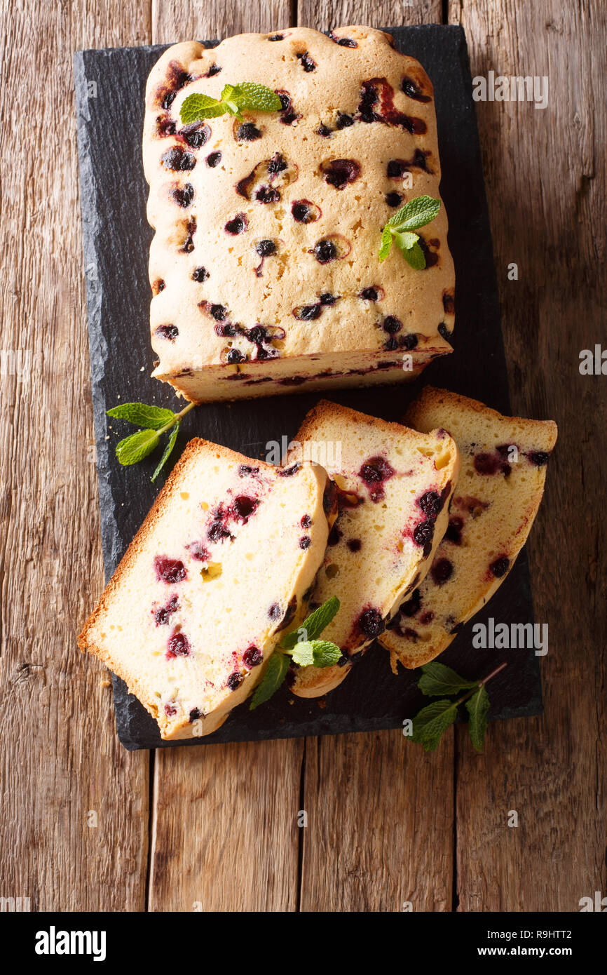 Sliced black currant cake with mint close-up on the table. Vertical top ...