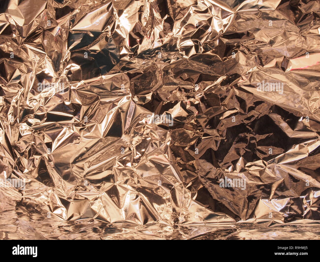 A surface with many faces. Silver metallic luster. Crumpled foil ...