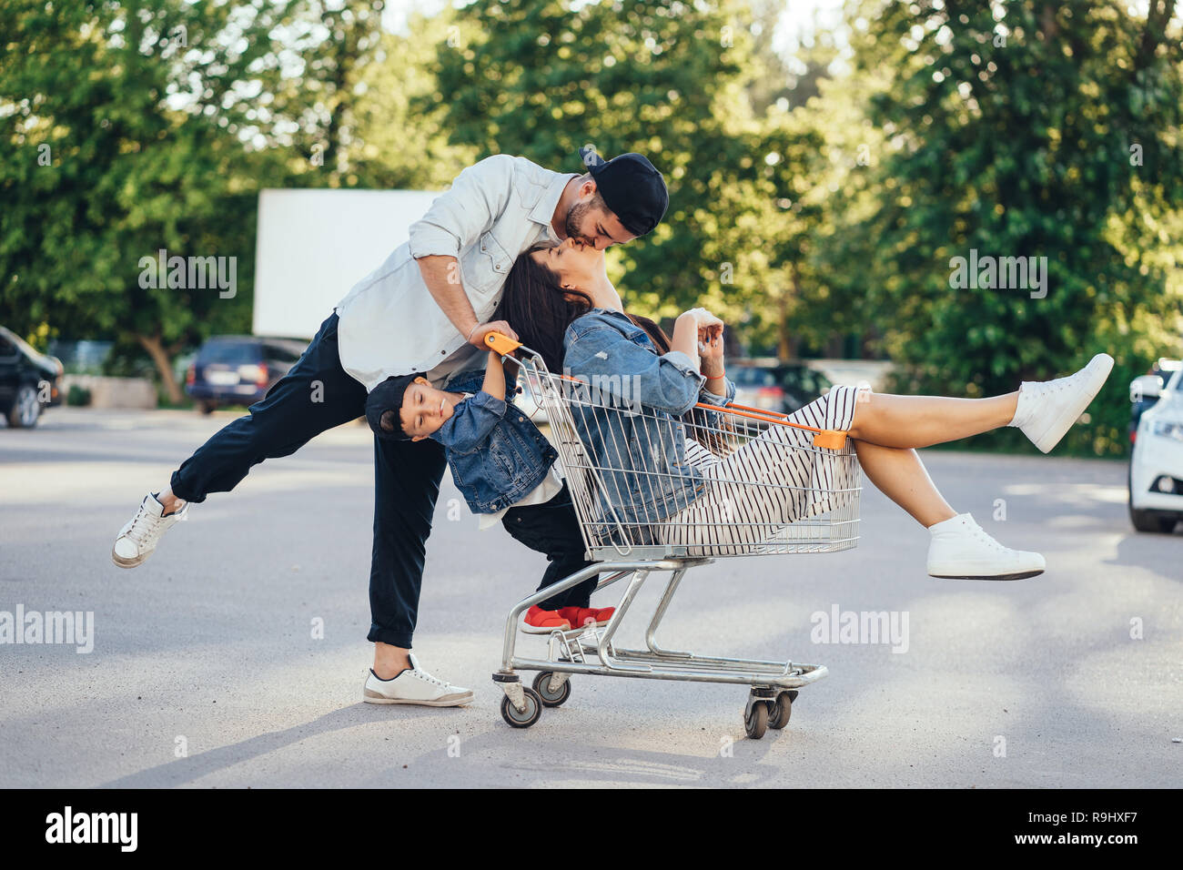 Young dad carries mom and son in a cart on the parking lot Stock Photo ...