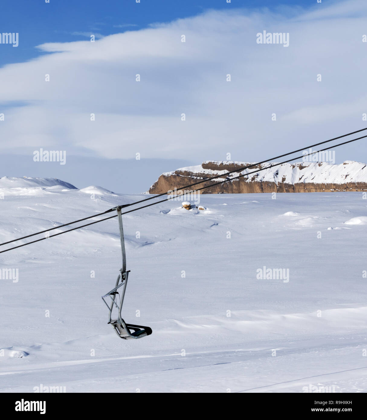 Snowy slope, chair-lift and blue sky with clouds at sun winter day ...